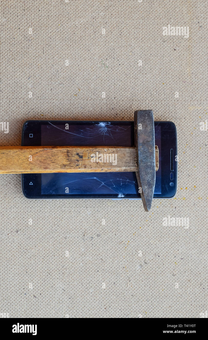 Hammer and smartphone. The screen of the smartphone, a broken hammer ...