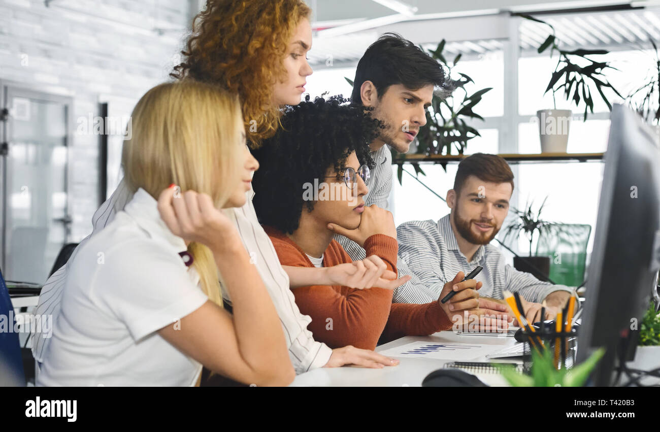 Pensive millennial team reading business information on computer Stock ...