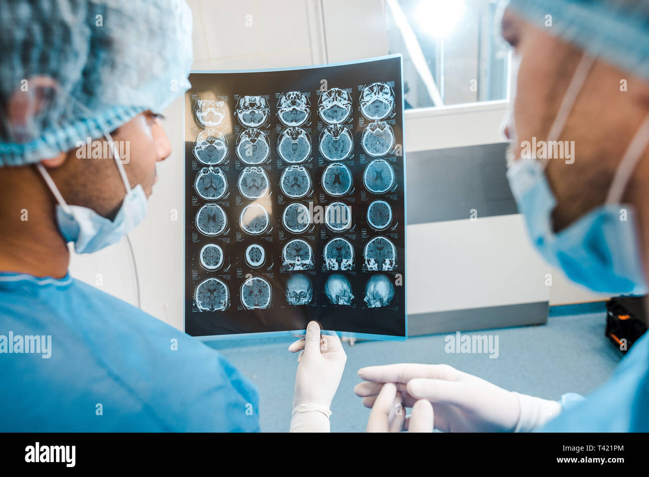 back view of doctors in uniforms and medical masks looking at x-ray ...