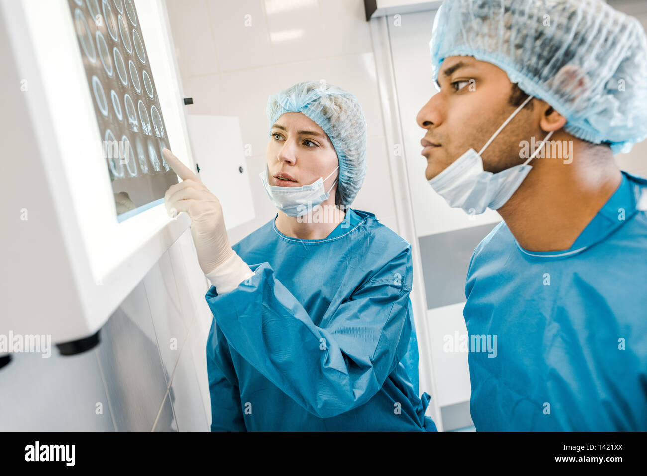 handsome and beautiful doctors in uniforms and medical masks pointing ...