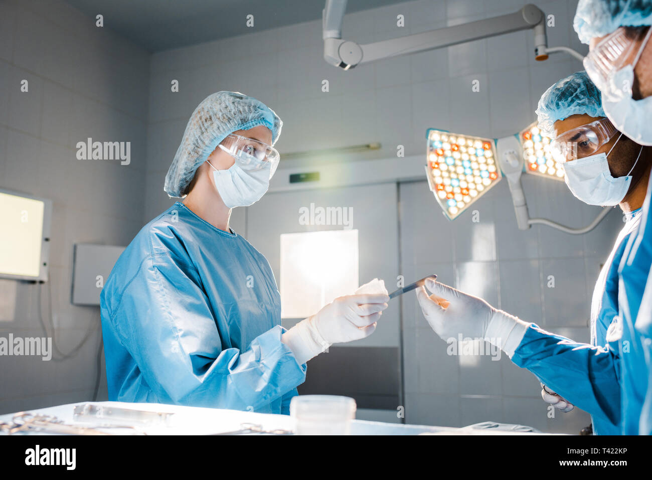 nurse in uniform and medical cap giving scalpel to doctor in operating ...