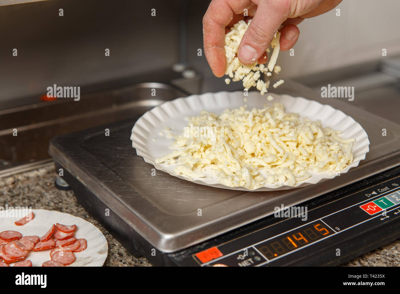 The chef measures on the scales the required amount of cheese for pizza ...