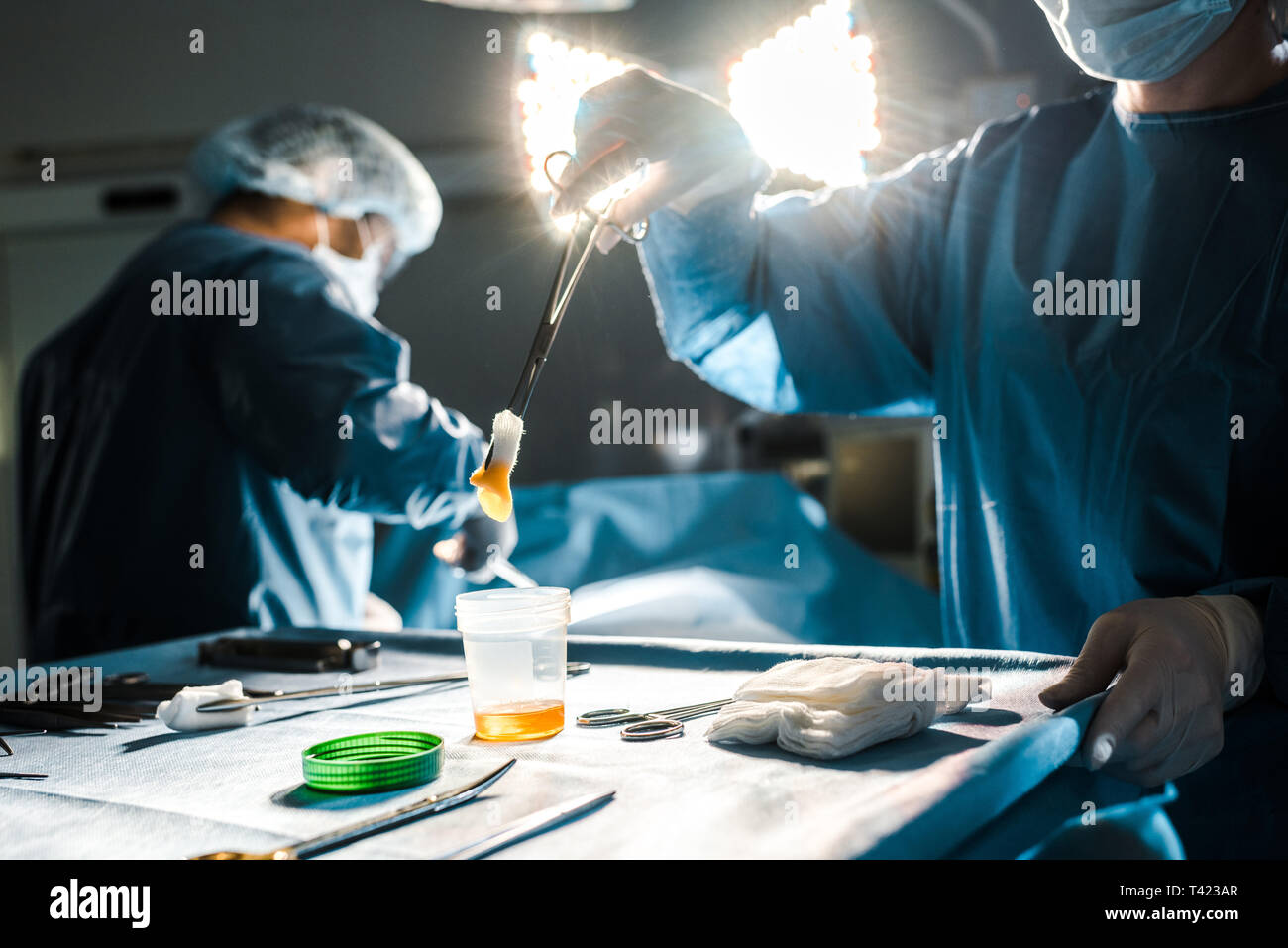 selective focus of surgeon doing operation and nurse holding tampon in ...