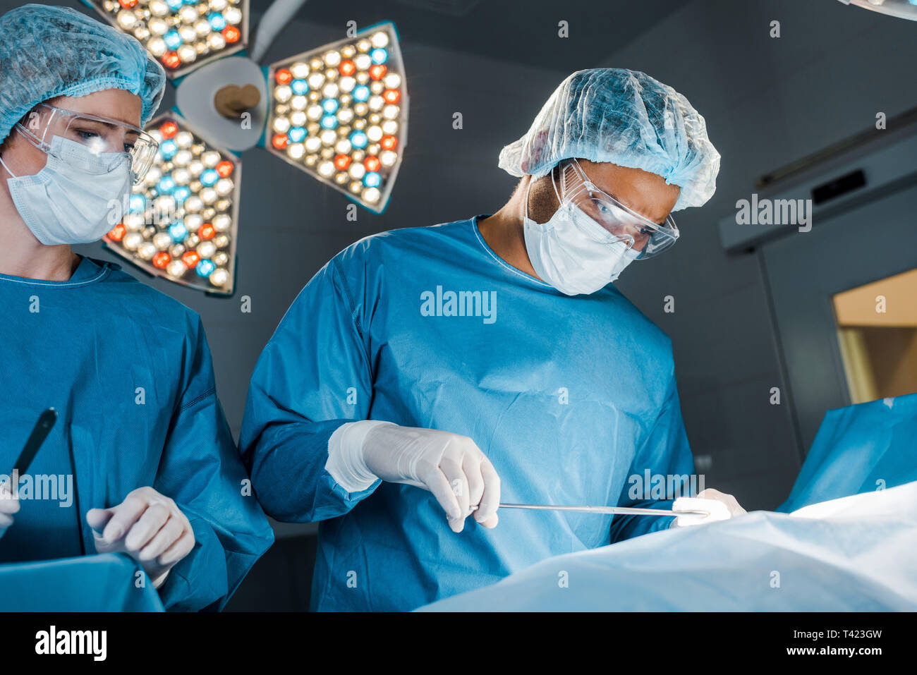 nurse and surgeon in uniforms and medical masks doing operation Stock ...