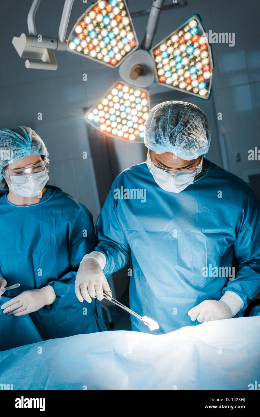 nurse and surgeon in uniforms and medical masks doing operation Stock ...