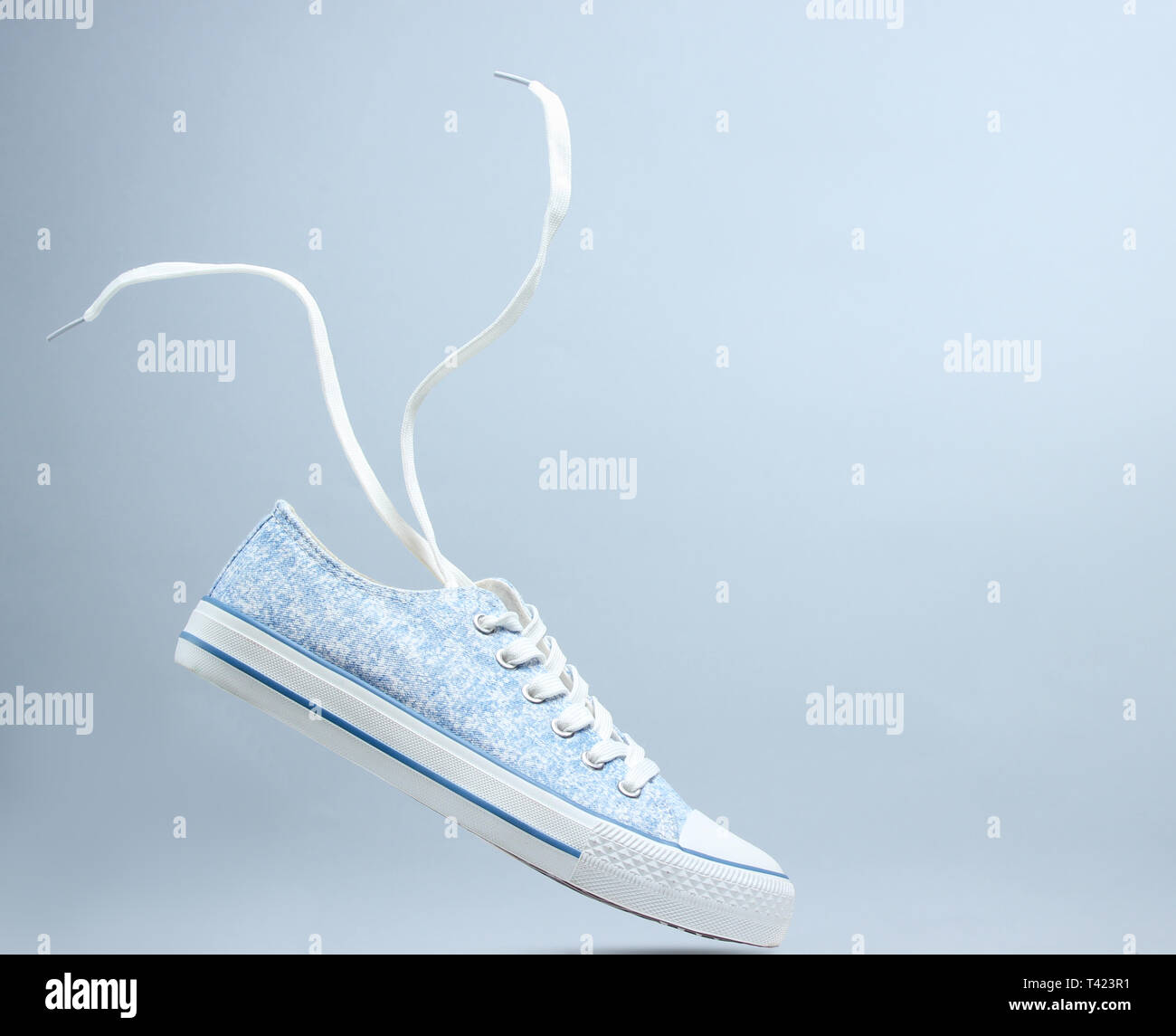 One White sneaker and floating laces on gray background, minimalism ...