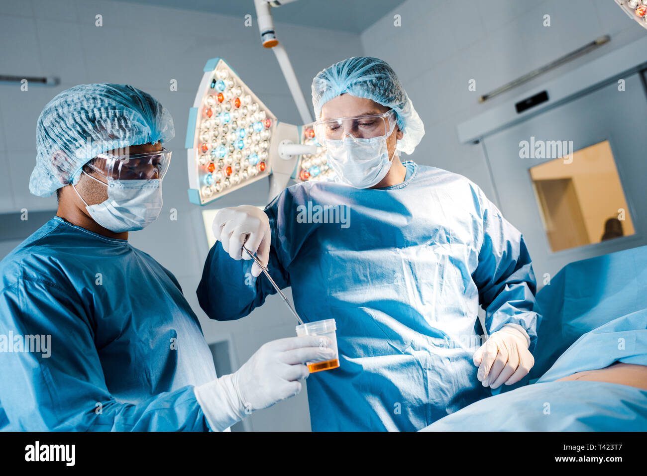 nurse and surgeon in uniforms and medical masks doing operation in ...