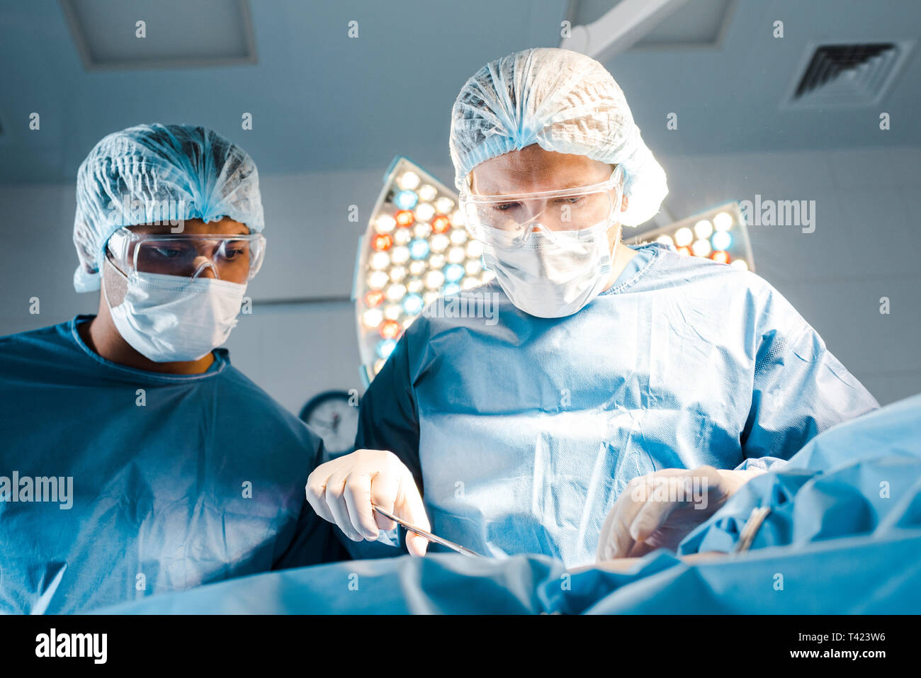 nurse and surgeon in uniforms and medical masks doing operation in ...