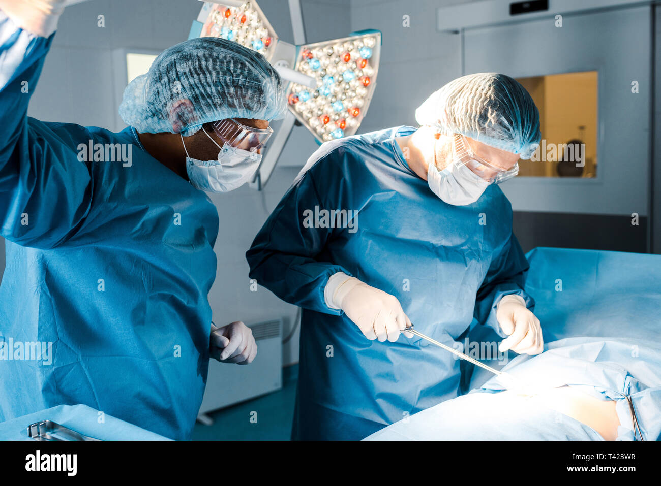 nurse and surgeon in uniforms and medical masks doing operation in ...