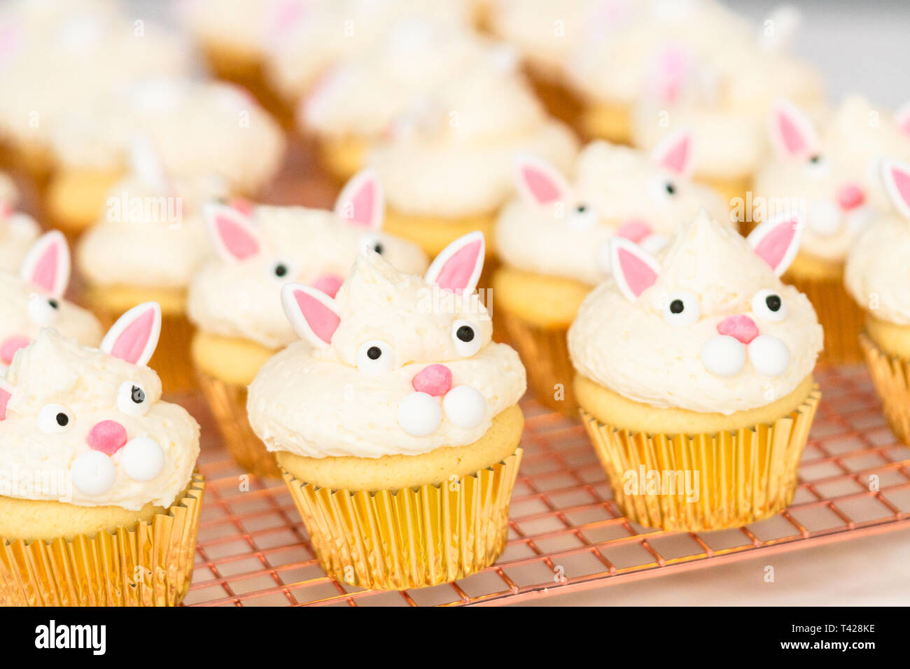 Decorating vanilla cupcakes with a white buttercream icing and bunny ...