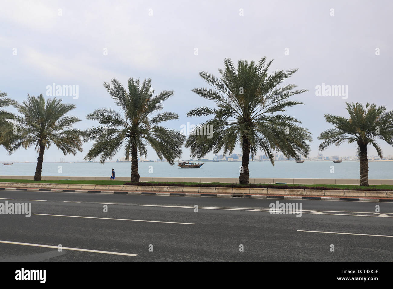 Doha, Qatar. 13th Apr, 2019. People walk on the corniche past palm ...