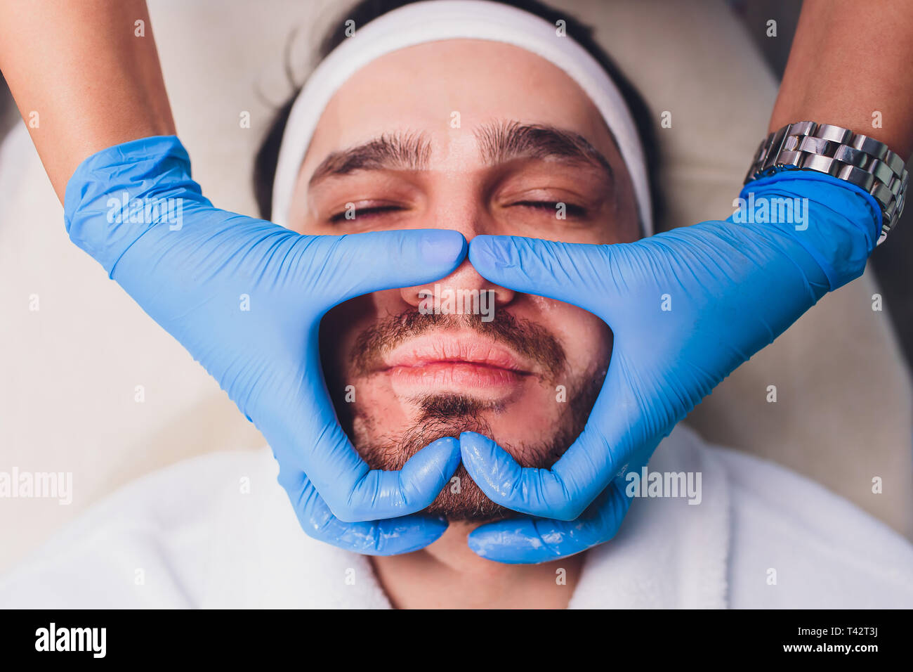 Female hands cleaning man's face with cotton swabs in a spa center ...