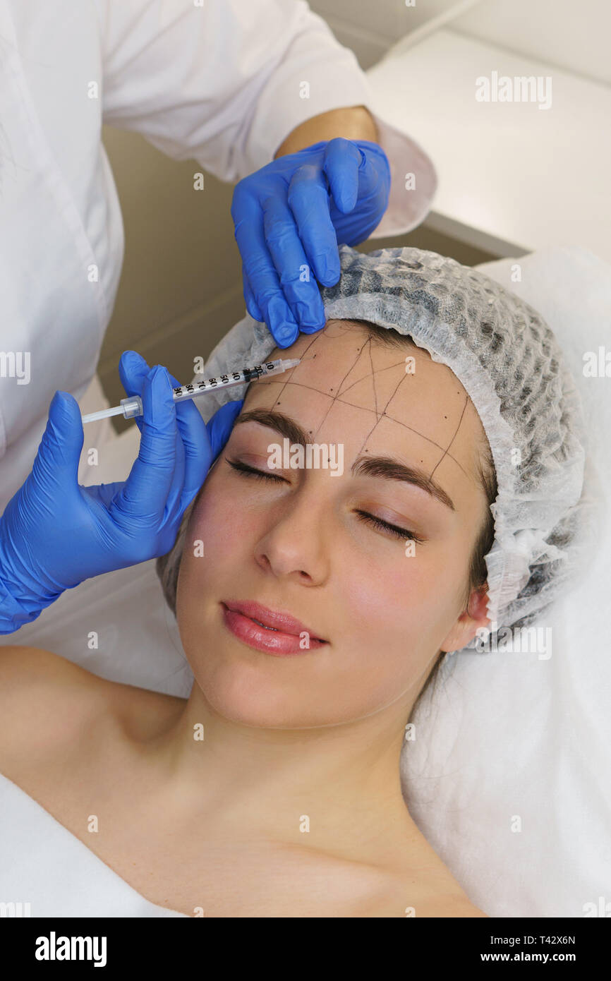 Aesthetic cosmetology. Hands of cosmetologist inject hyaluronic acid in ...