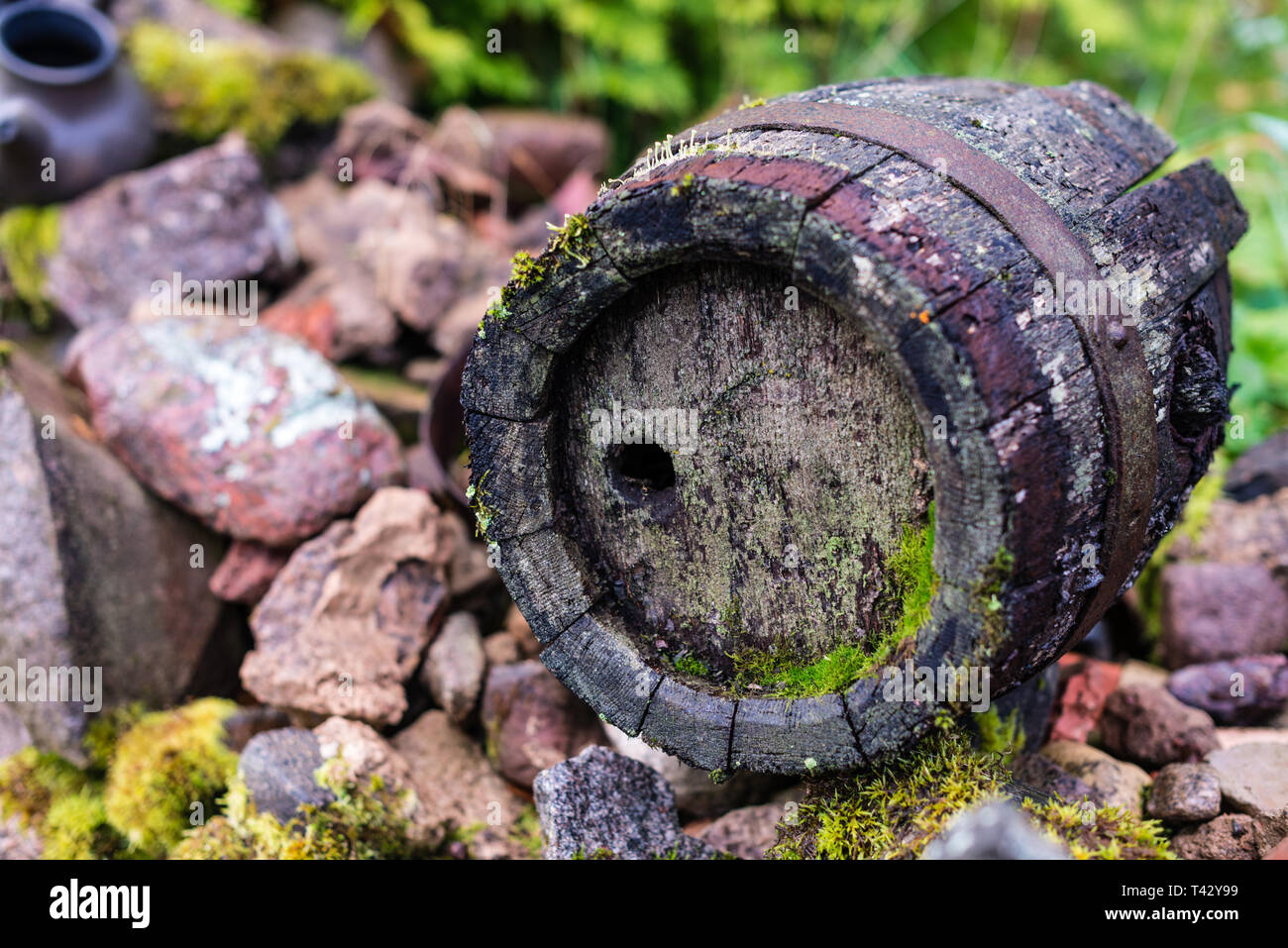Black clay jug and old wooden barrel on stone pile Stock Photo - Alamy
