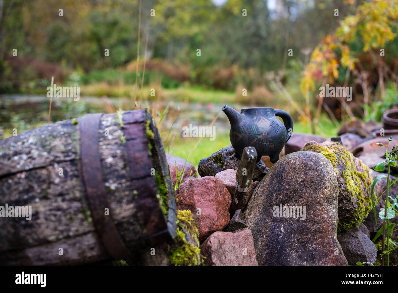 Black clay jug and old wooden barrel on stone pile Stock Photo - Alamy