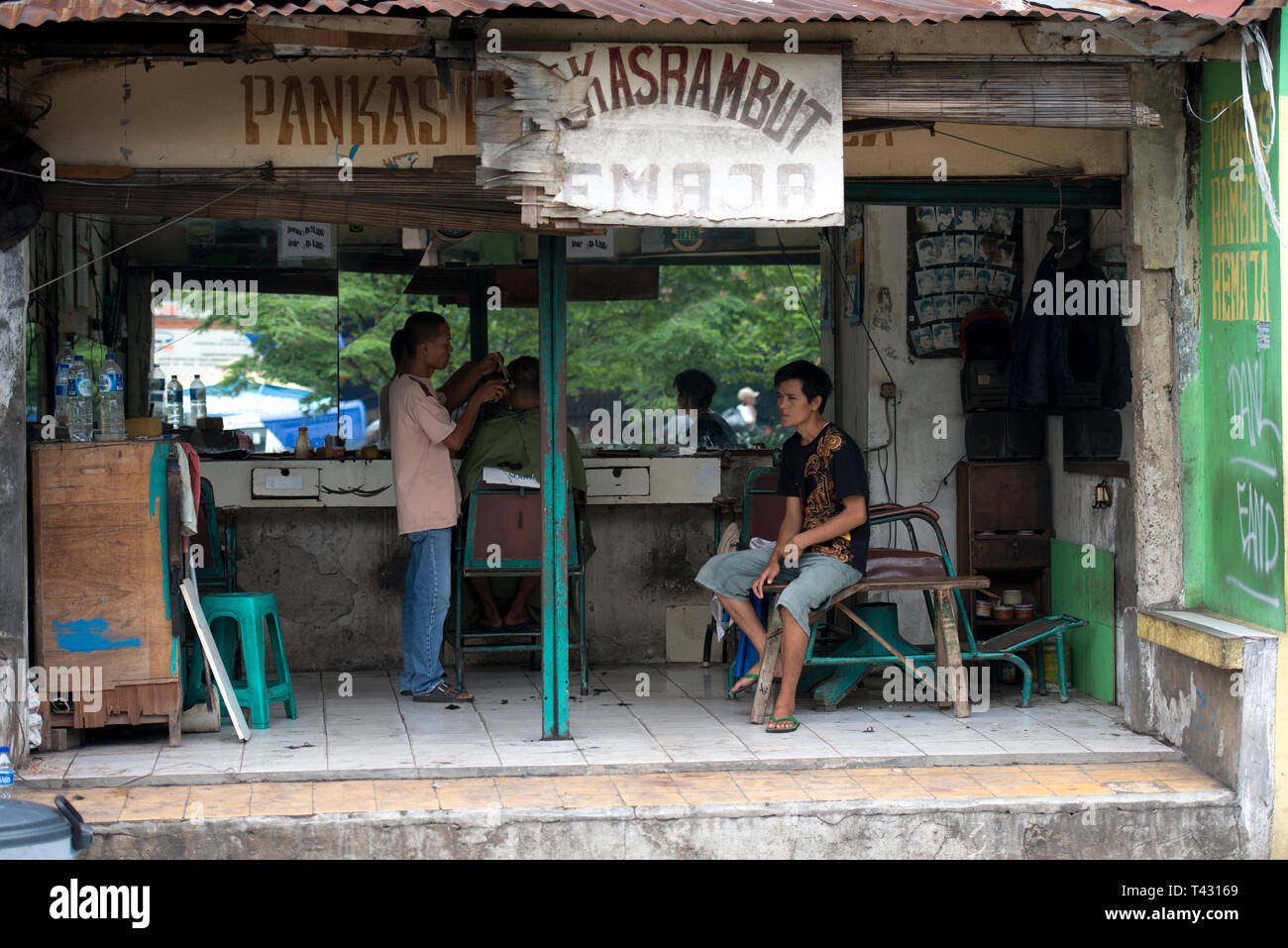 Man having haircut, in open barber shop by road, Manggarai district ...