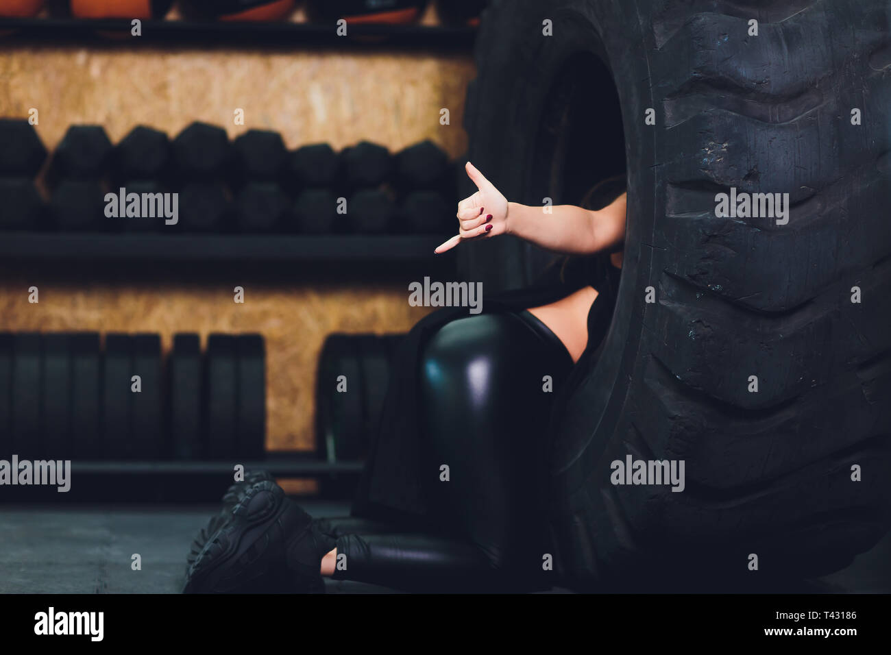 Fit female athlete working out with a huge tire, turning and carry in ...