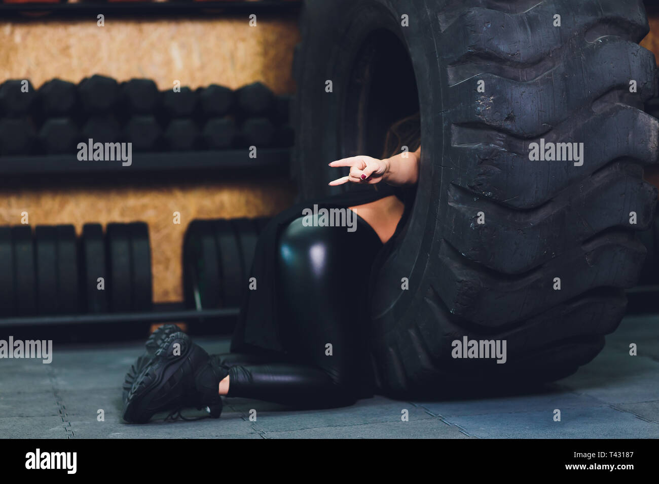 Fit female athlete working out with a huge tire, turning and carry in ...