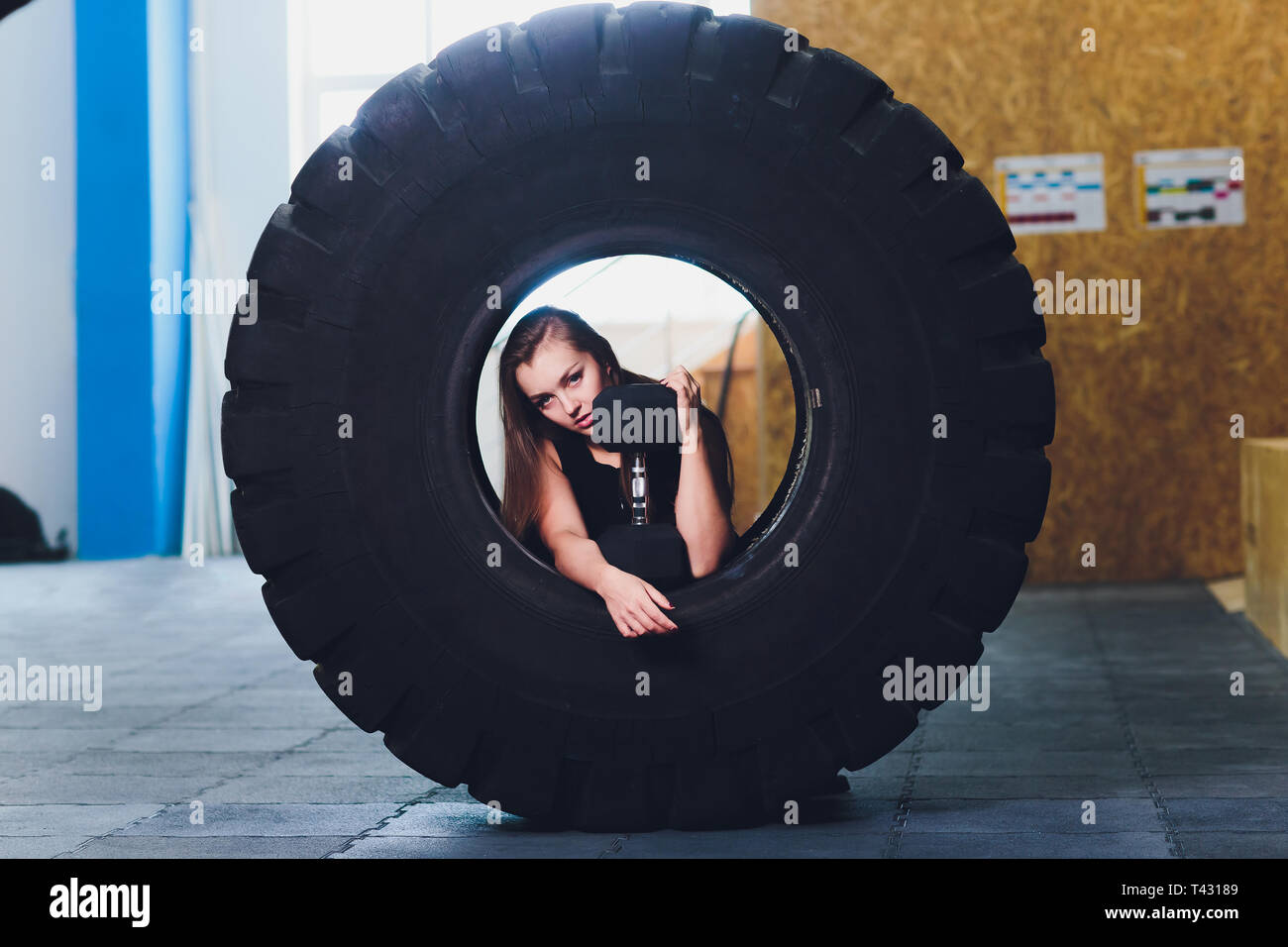Fit female athlete working out with a huge tire, turning and carry in ...