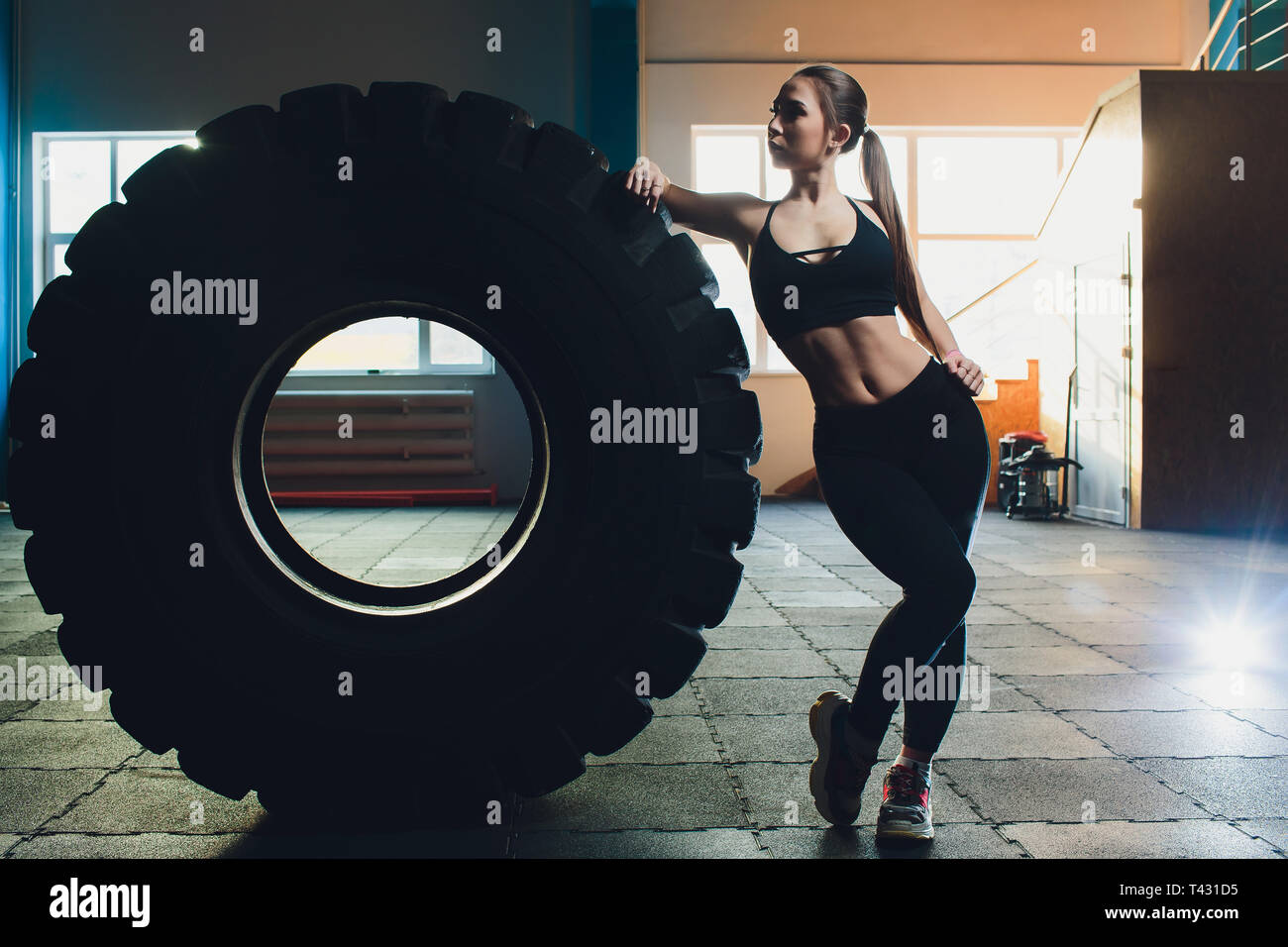 Fitness woman flipping wheel tire in gym. Fit female athlete working ...