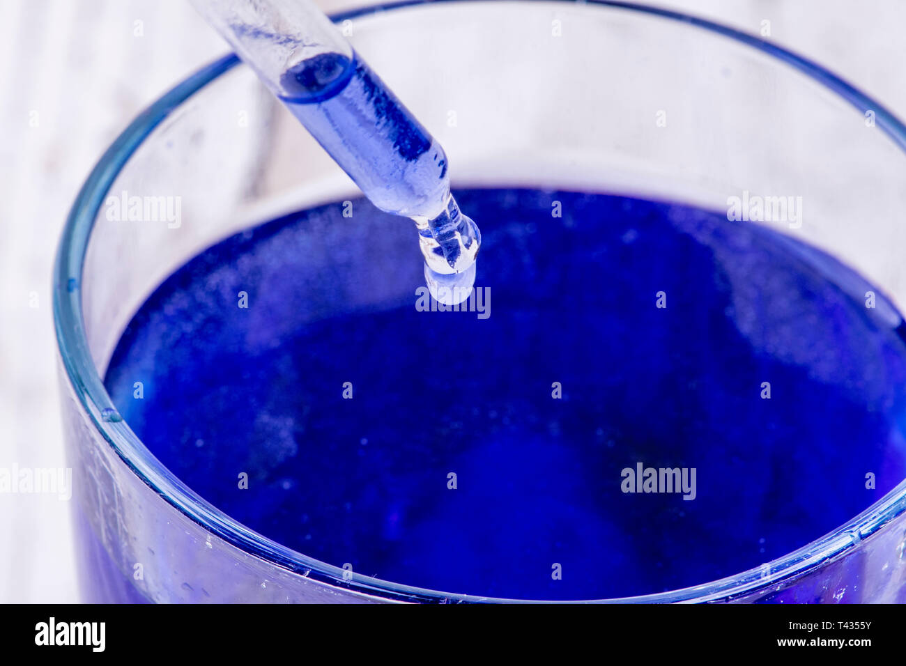 drop blue liquid into a glass with a pipette Stock Photo - Alamy