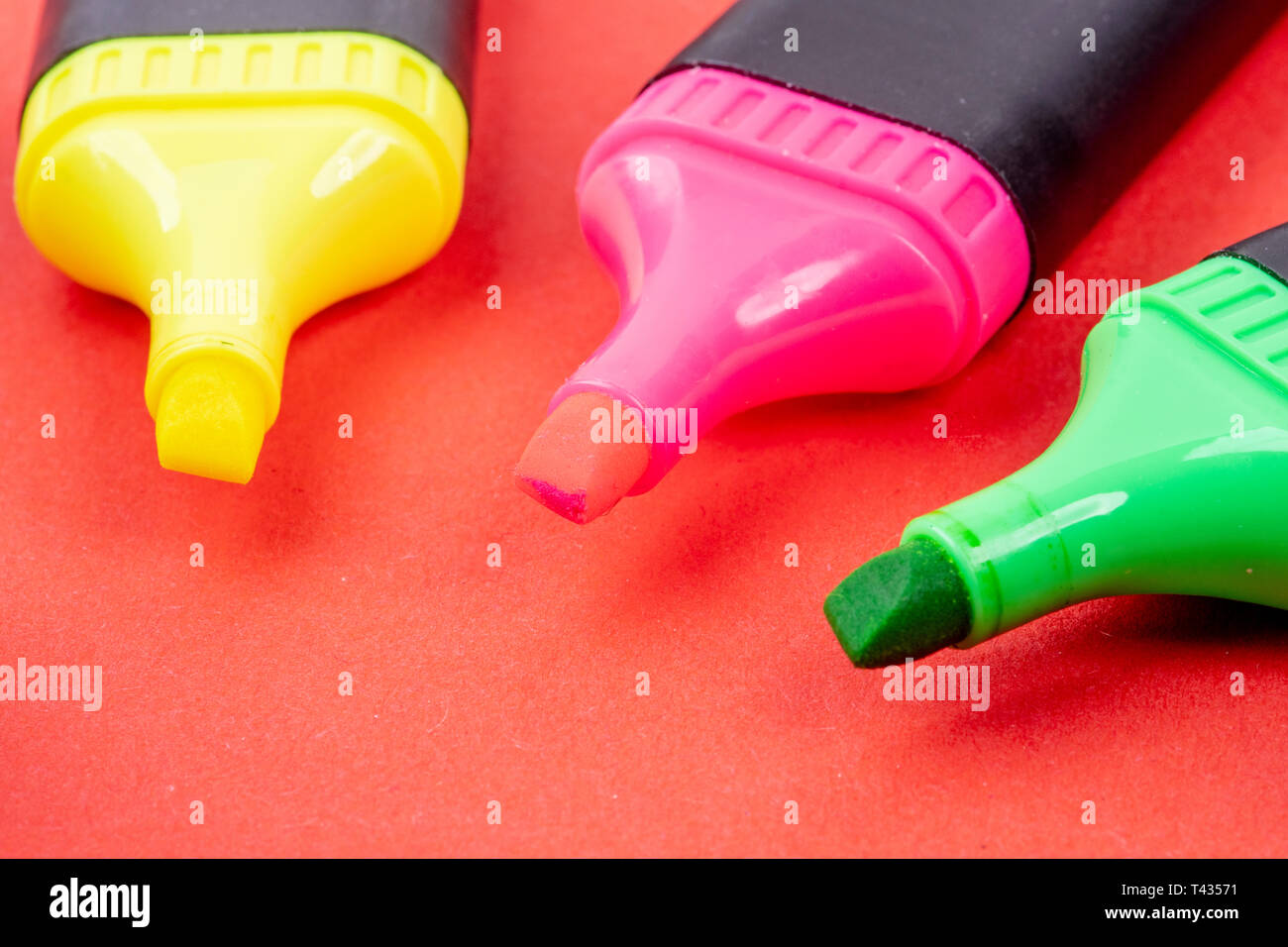 three highlighters in yellow pink and green on a red background Stock ...