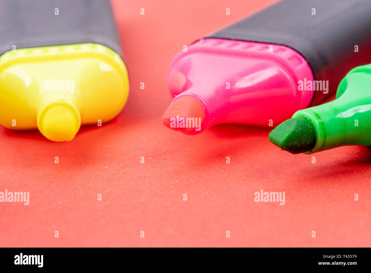 three highlighters in yellow pink and green on a red background Stock ...