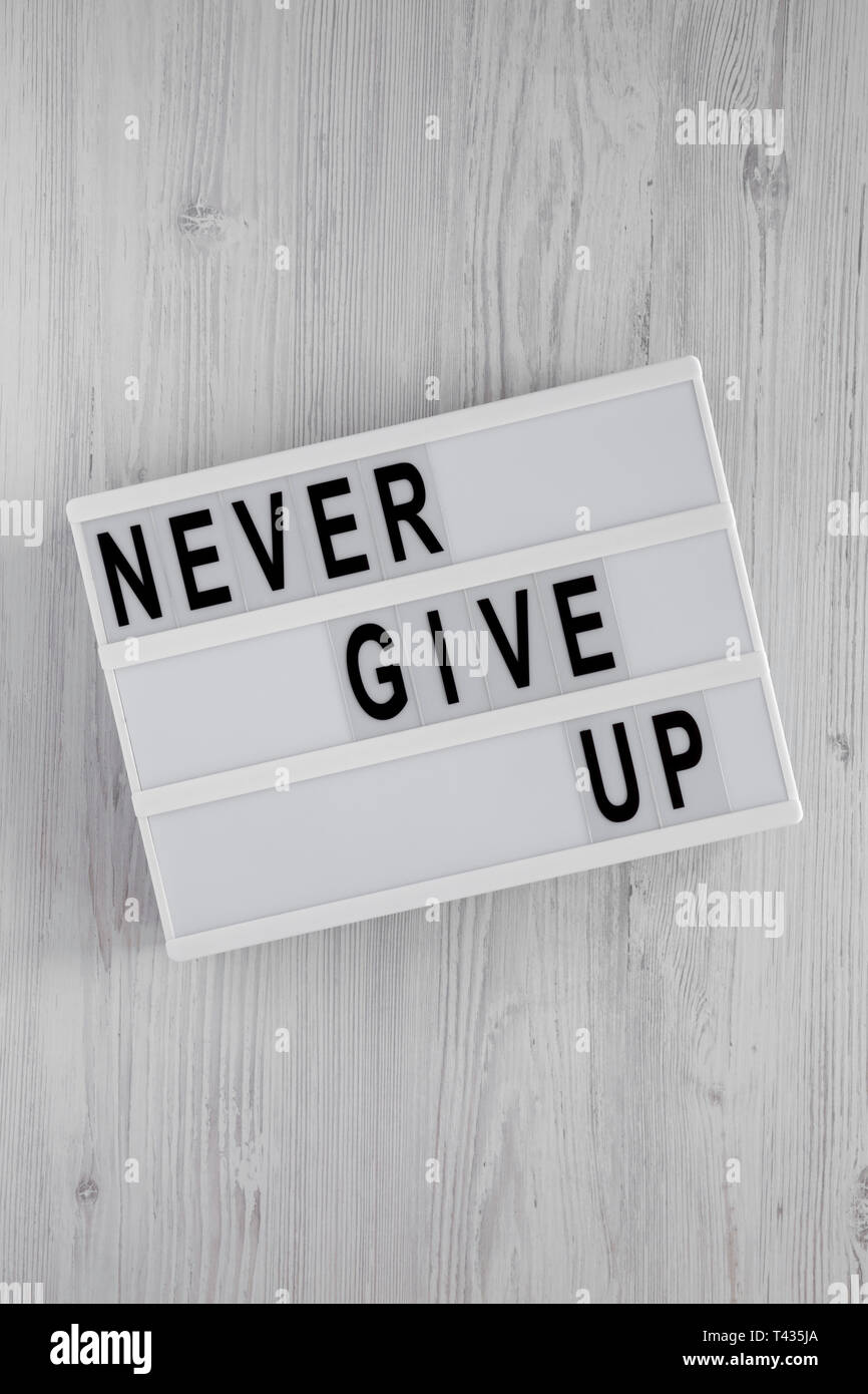 'Never give up' words on lightbox over white wooden background. Flat ...