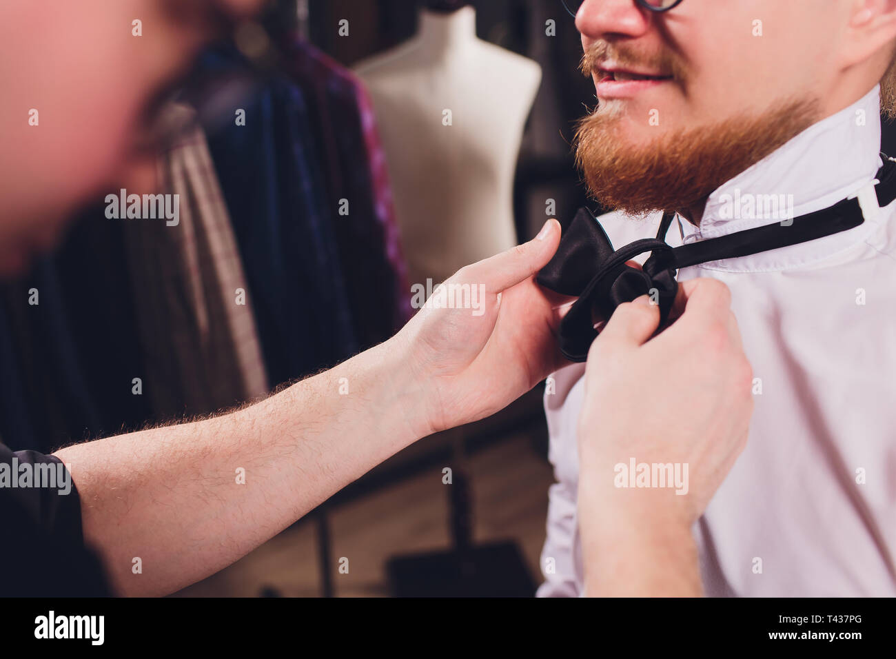 Male customer at shopping mall trying business clothes, shop assistant ...