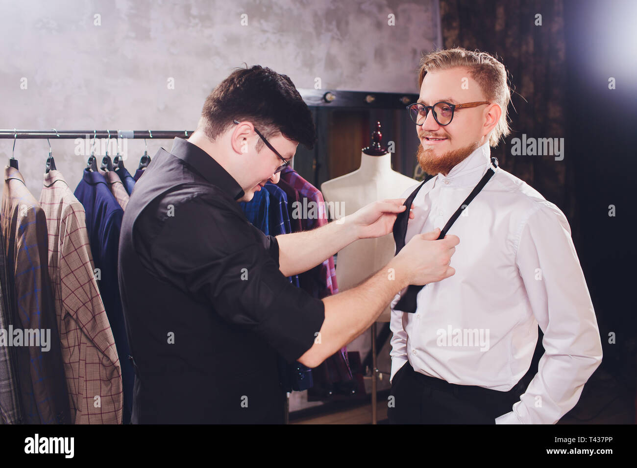 Male customer at shopping mall trying business clothes, shop assistant ...