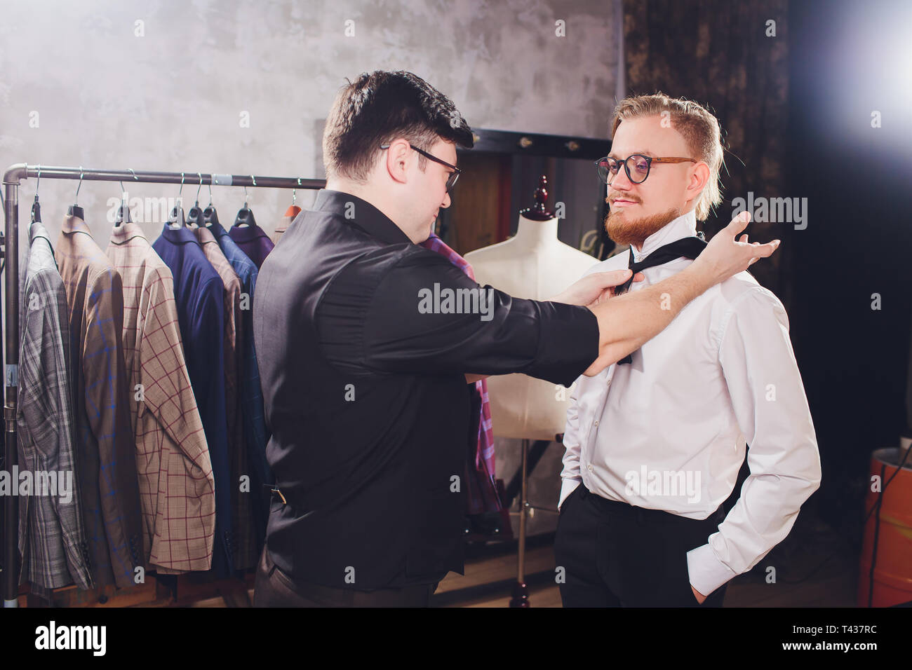 Male customer at shopping mall trying business clothes, shop assistant ...