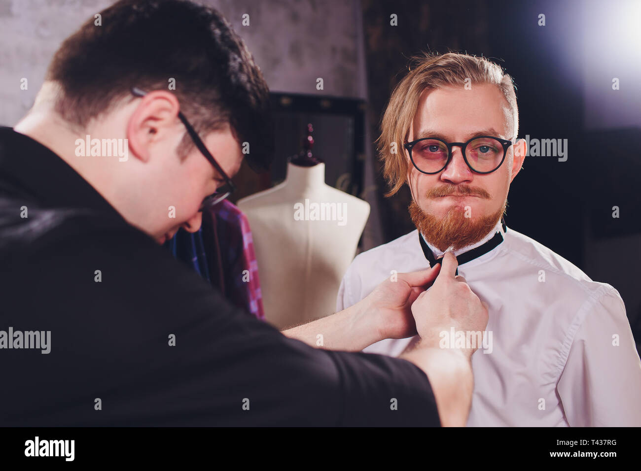 Male customer at shopping mall trying business clothes, shop assistant ...