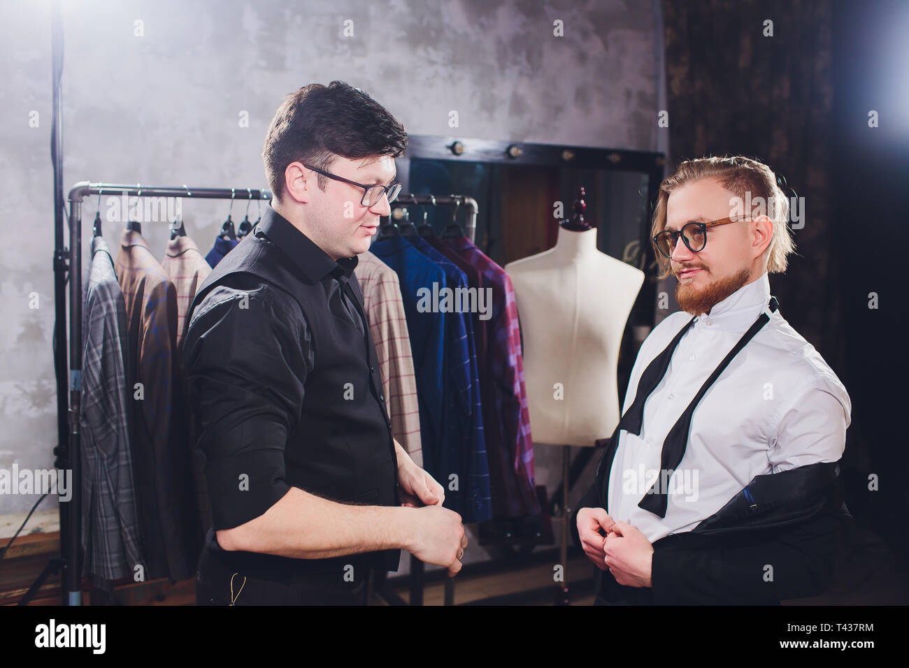 Male customer at shopping mall trying business clothes, shop assistant ...