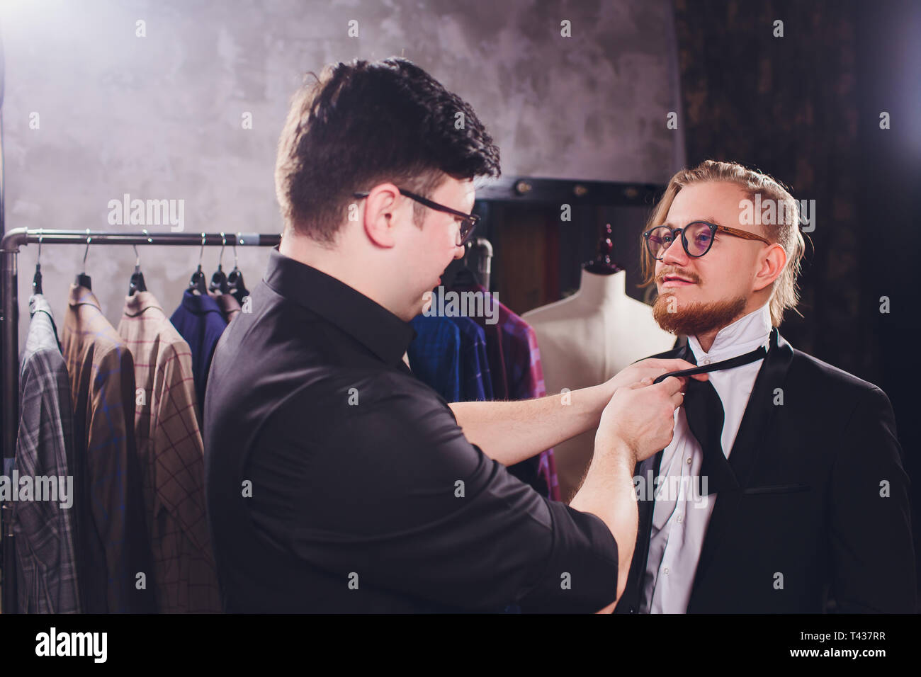 Male customer at shopping mall trying business clothes, shop assistant ...