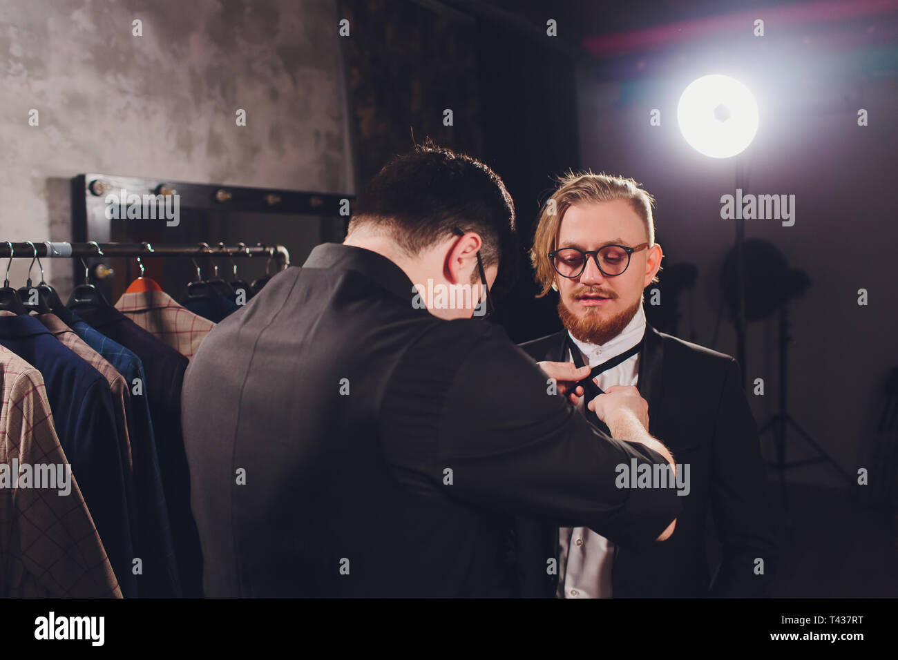 Male customer at shopping mall trying business clothes, shop assistant ...