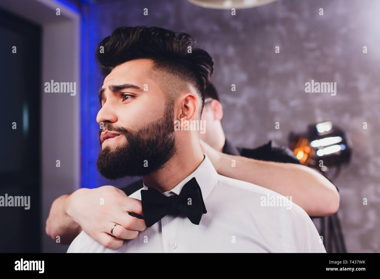 Male customer at shopping mall trying business clothes, shop assistant ...