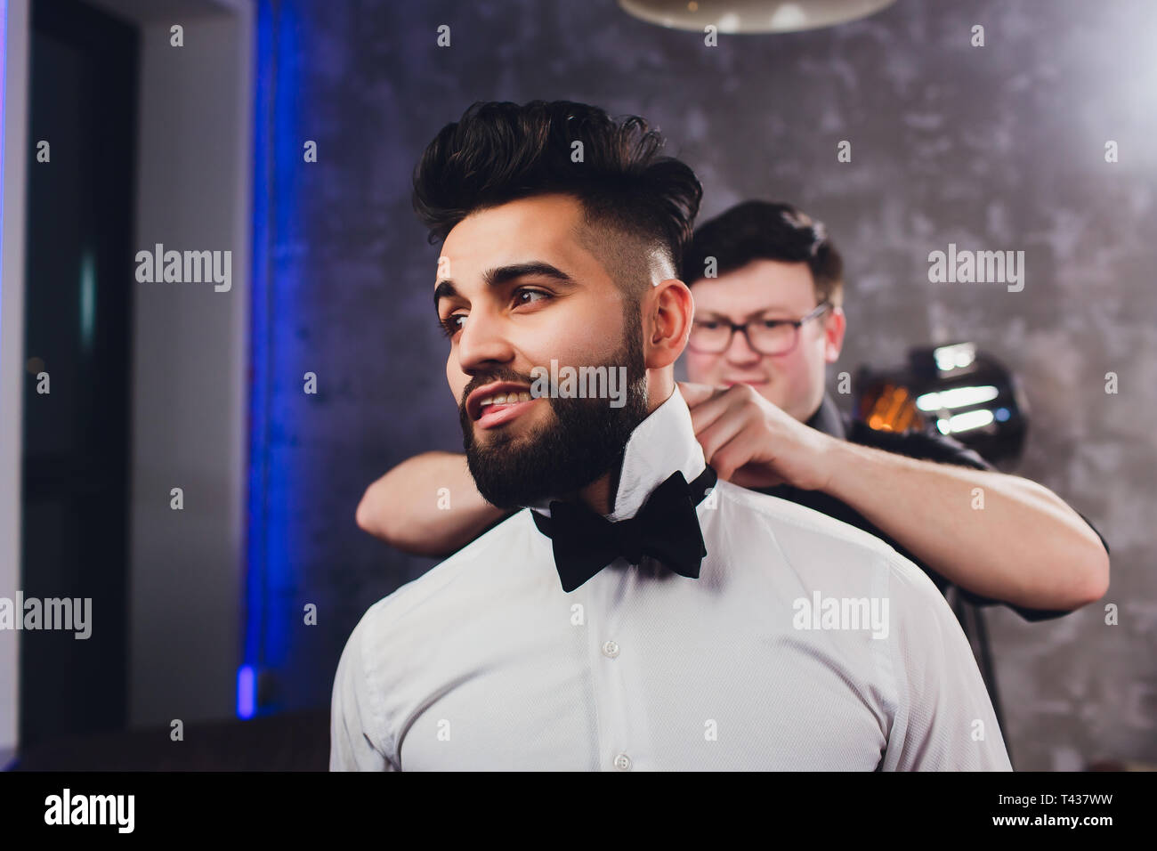 Male customer at shopping mall trying business clothes, shop assistant ...