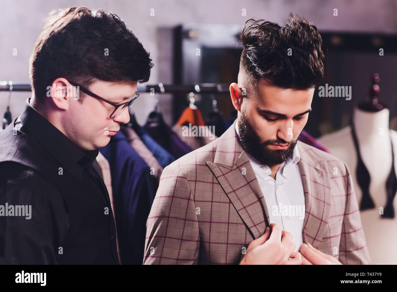 Male customer at shopping mall trying business clothes, shop assistant ...