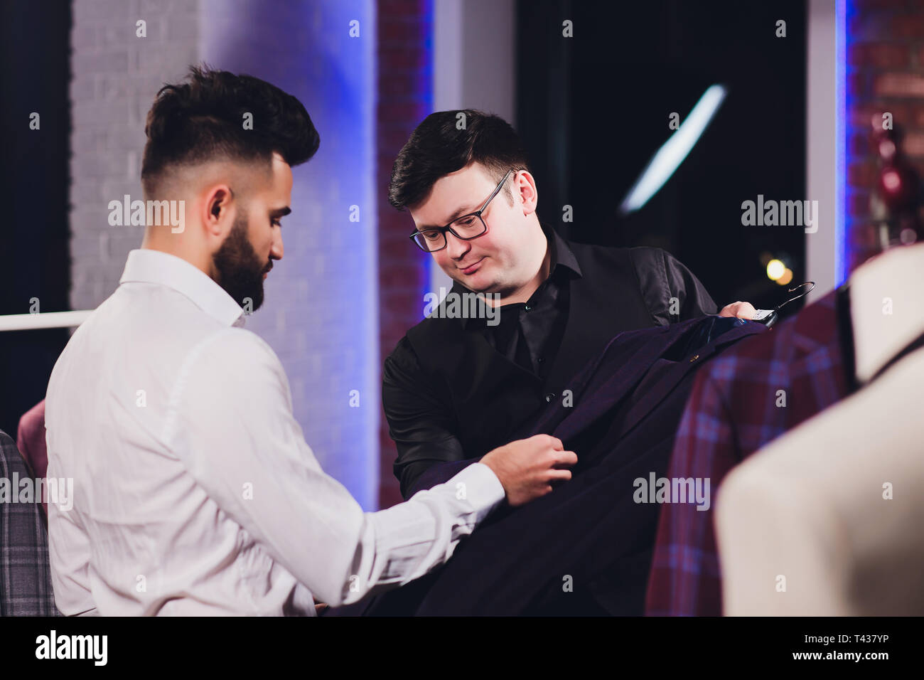 Male customer at shopping mall trying business clothes, shop assistant ...