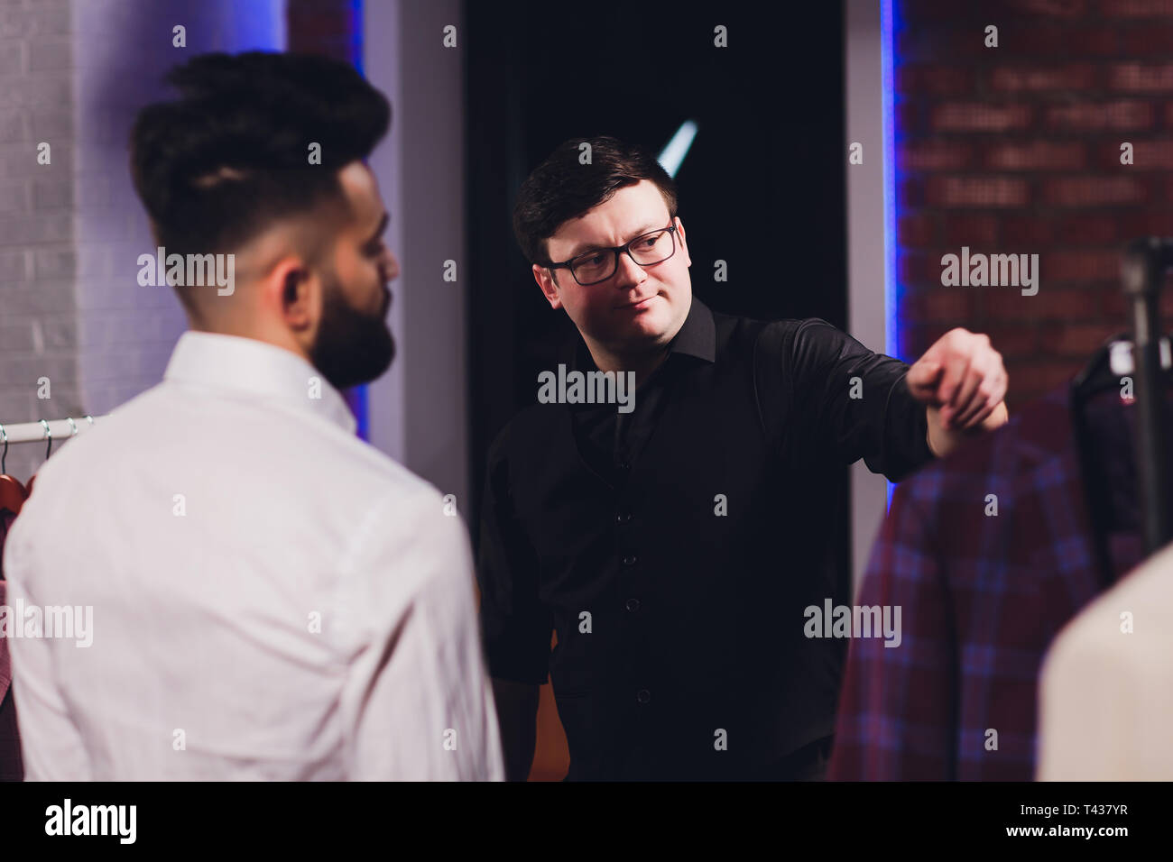 Male customer at shopping mall trying business clothes, shop assistant ...