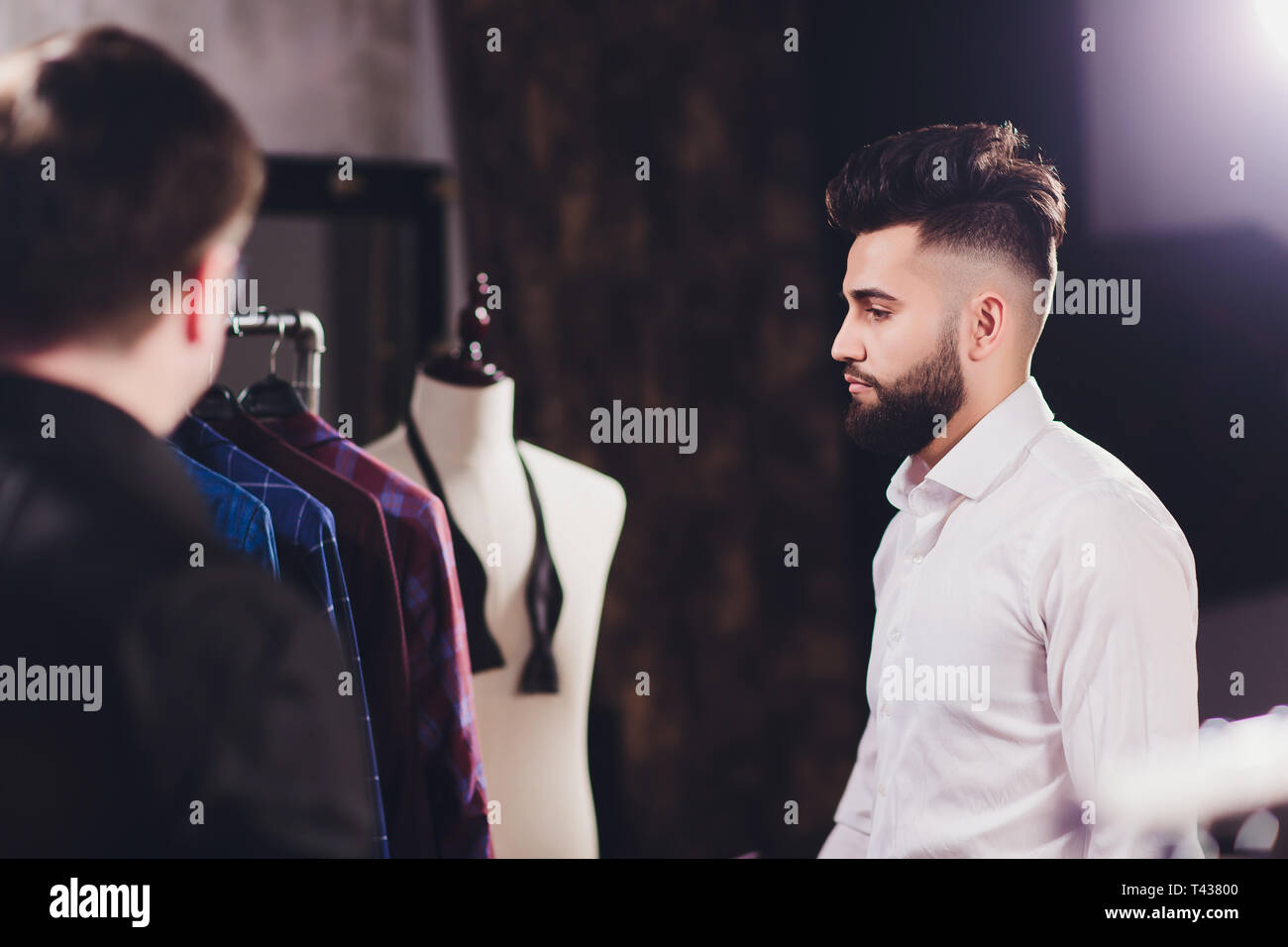 Male customer at shopping mall trying business clothes, shop assistant ...