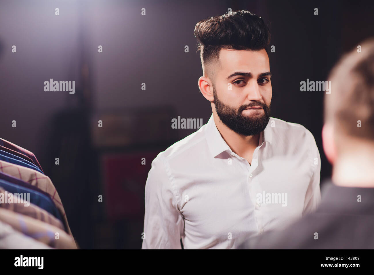 Male customer at shopping mall trying business clothes, shop assistant ...