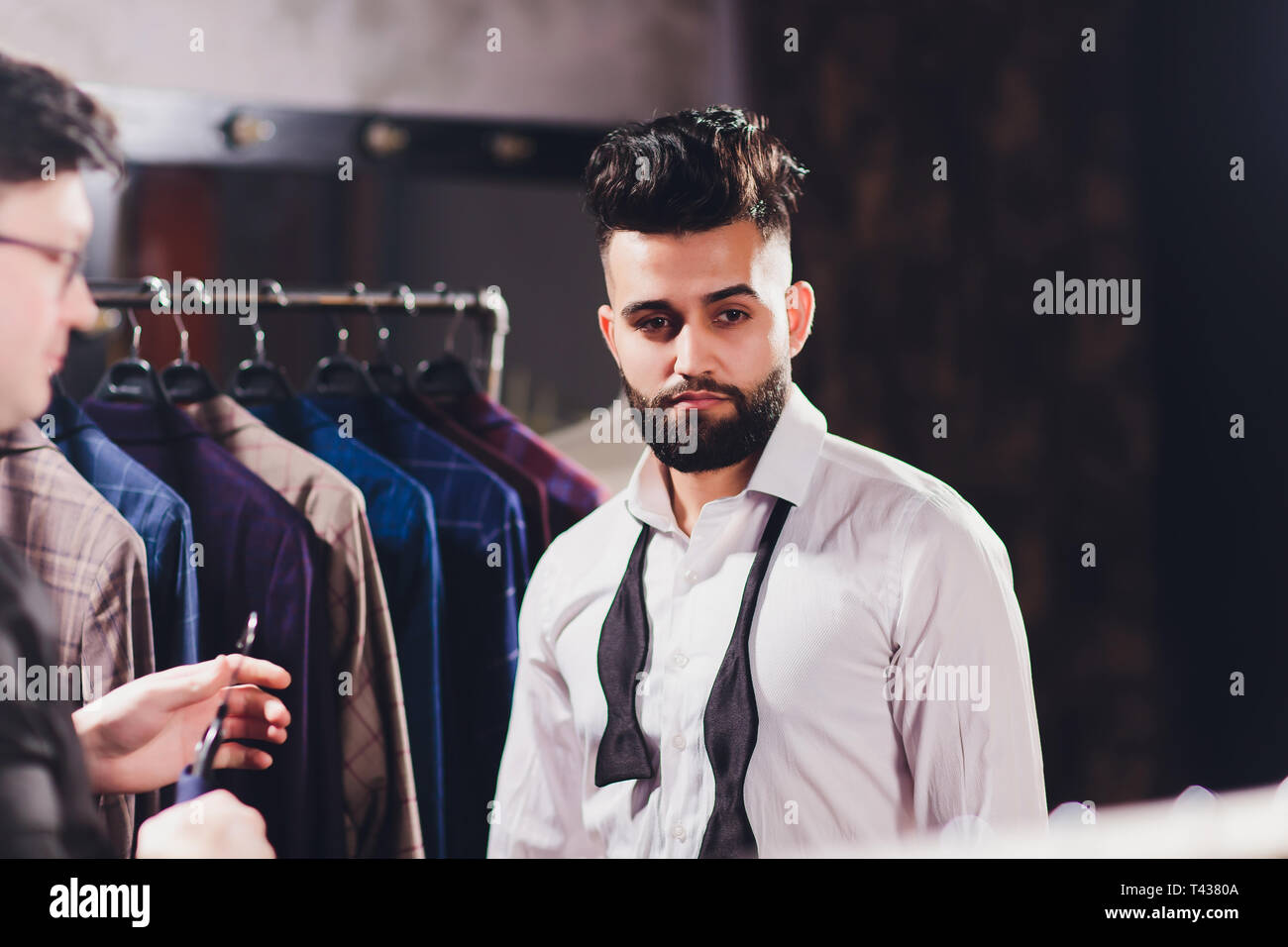 Male customer at shopping mall trying business clothes, shop assistant ...