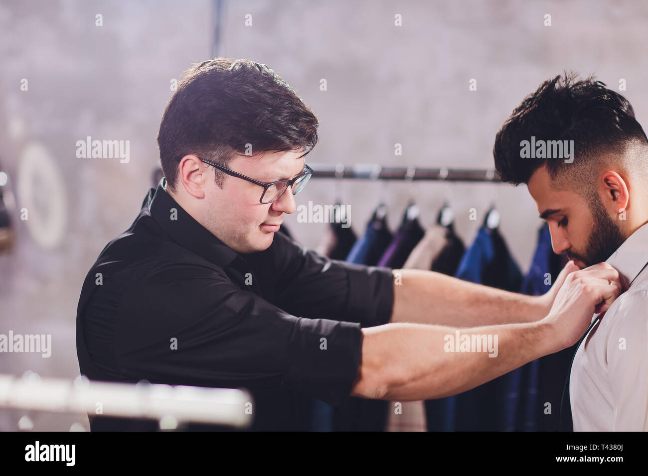 Male customer at shopping mall trying business clothes, shop assistant ...