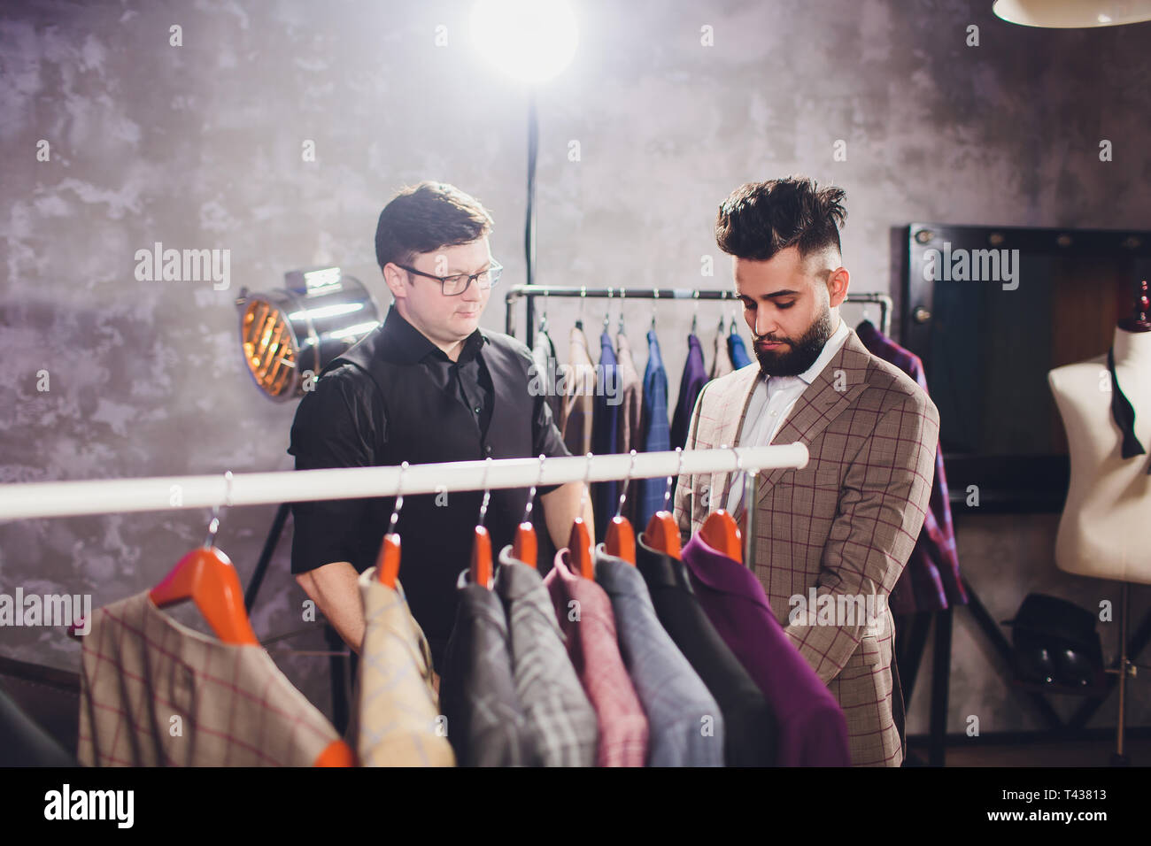 Male customer at shopping mall trying business clothes, shop assistant ...