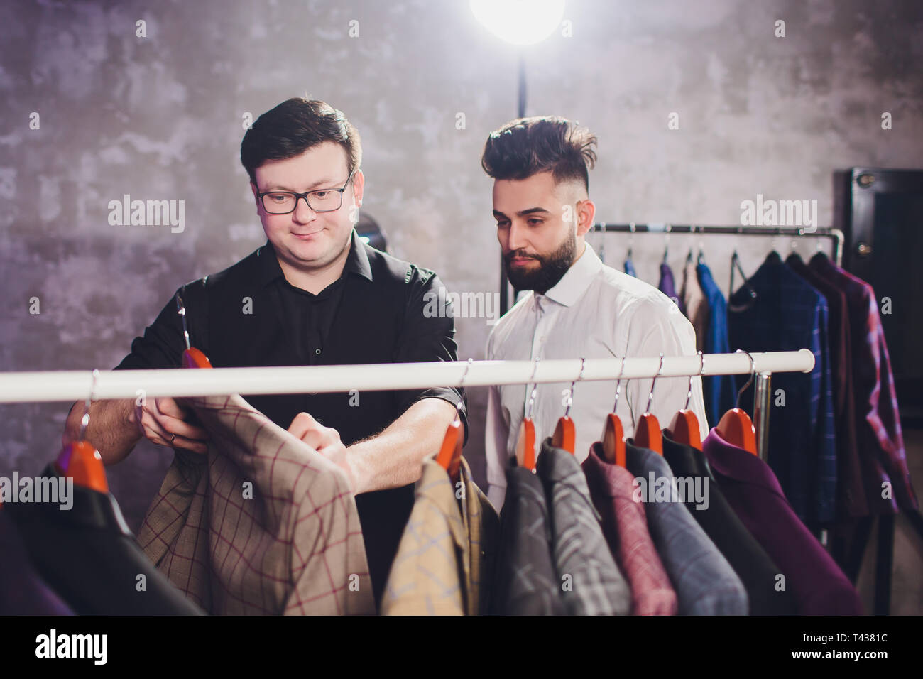 Male customer at shopping mall trying business clothes, shop assistant ...
