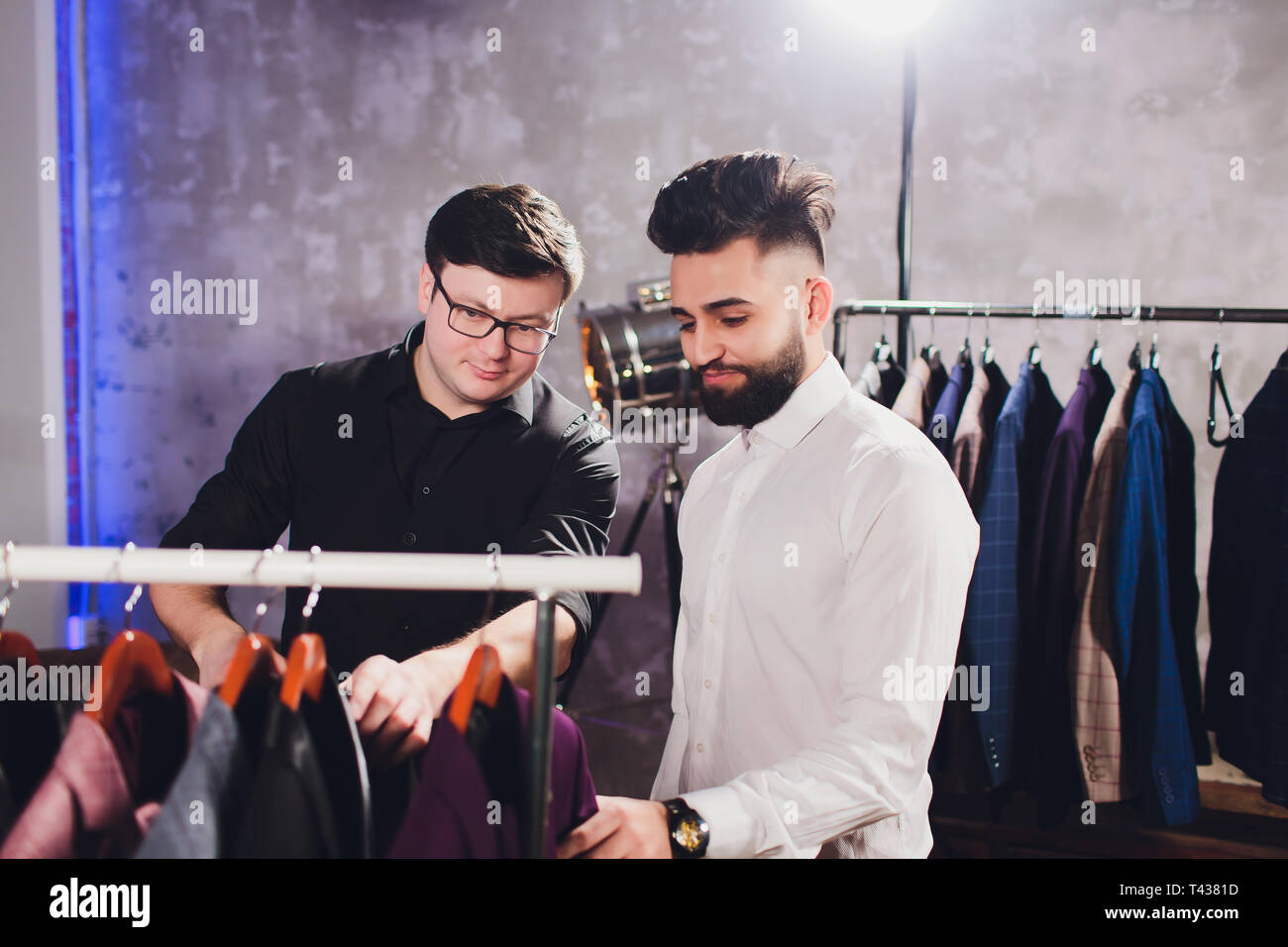 Male customer at shopping mall trying business clothes, shop assistant ...