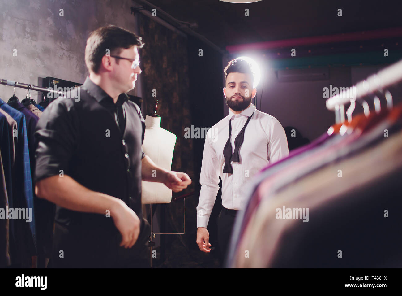 Male customer at shopping mall trying business clothes, shop assistant ...