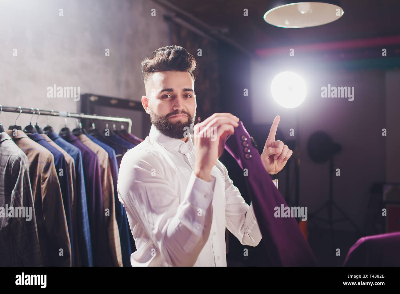 Male customer at shopping mall trying business clothes, shop assistant ...