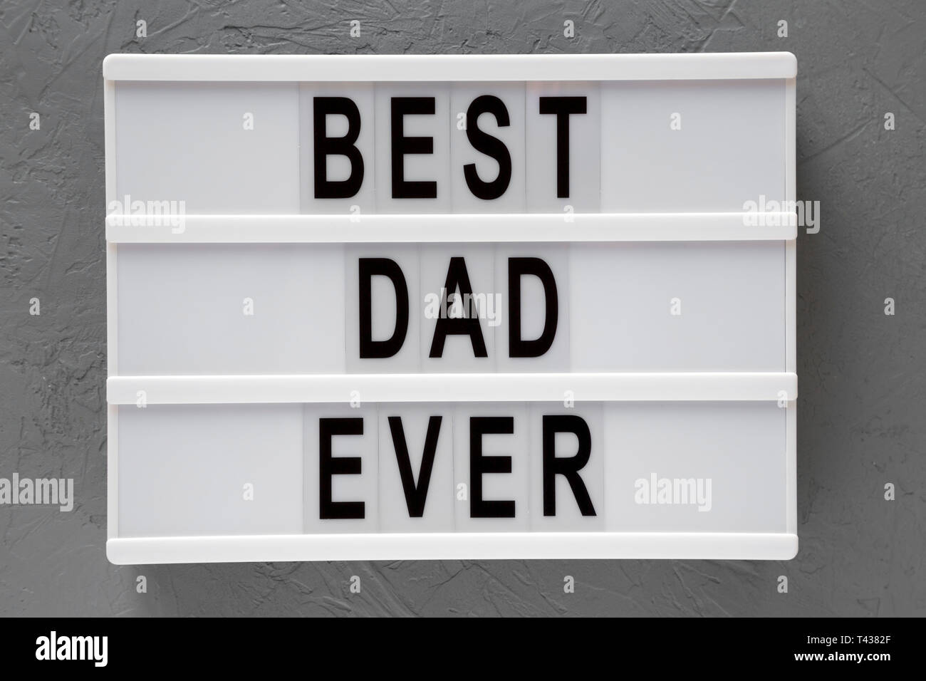 'Best dad ever' words on lightbox over gray surface, top view. Overhead ...